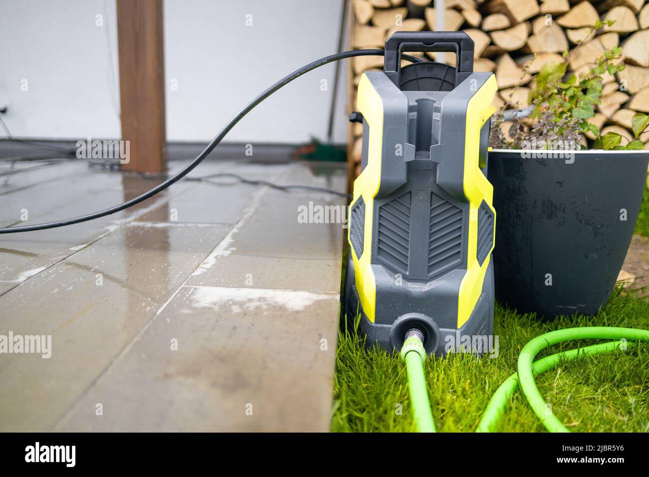 Pressure washer cleaning machine on wet concrete floor near the house ...