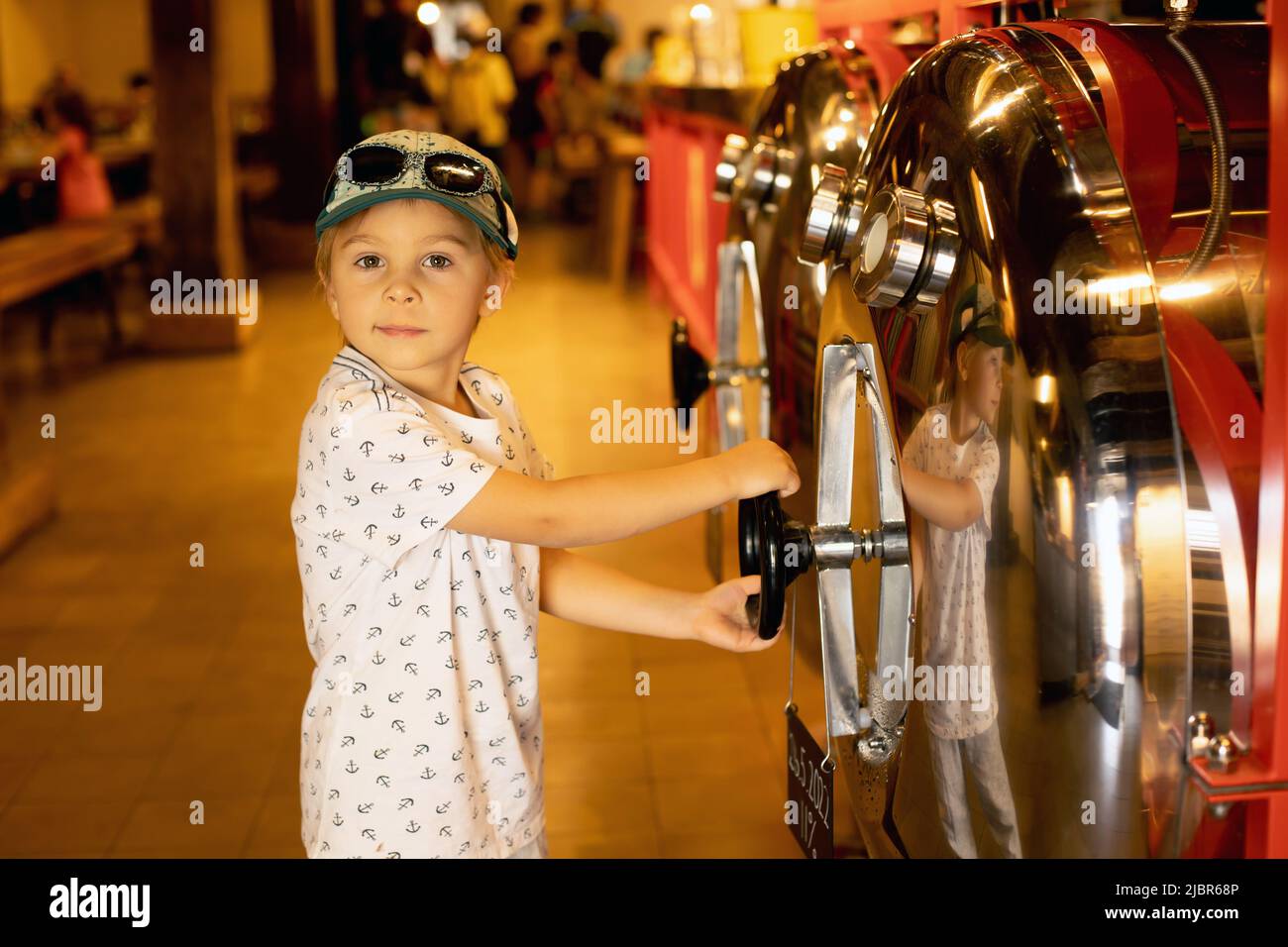 Preschool child, standing next to a barrel brewer for beer in a bar ...