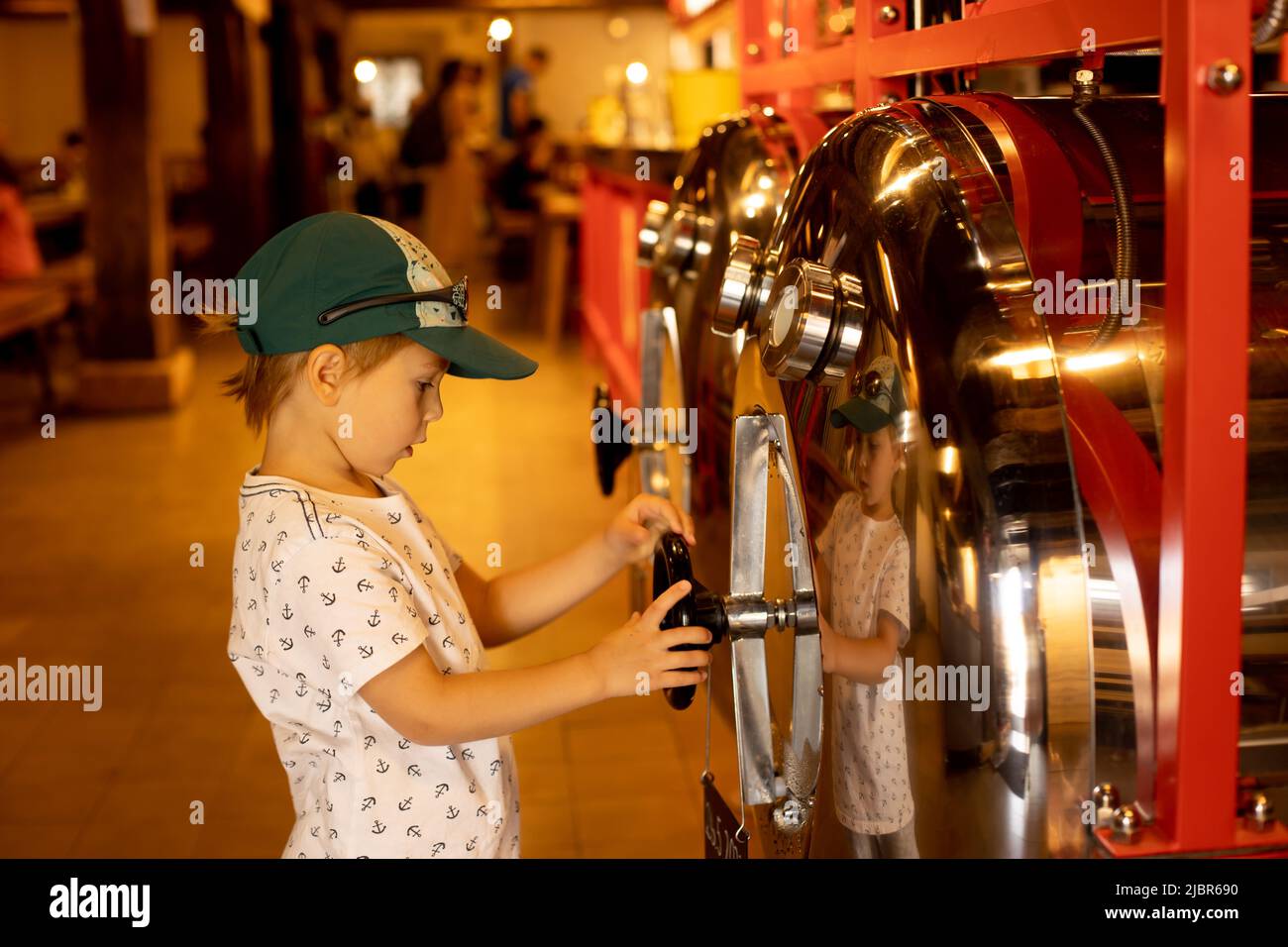 Preschool child, standing next to a barrel brewer for beer in a bar ...
