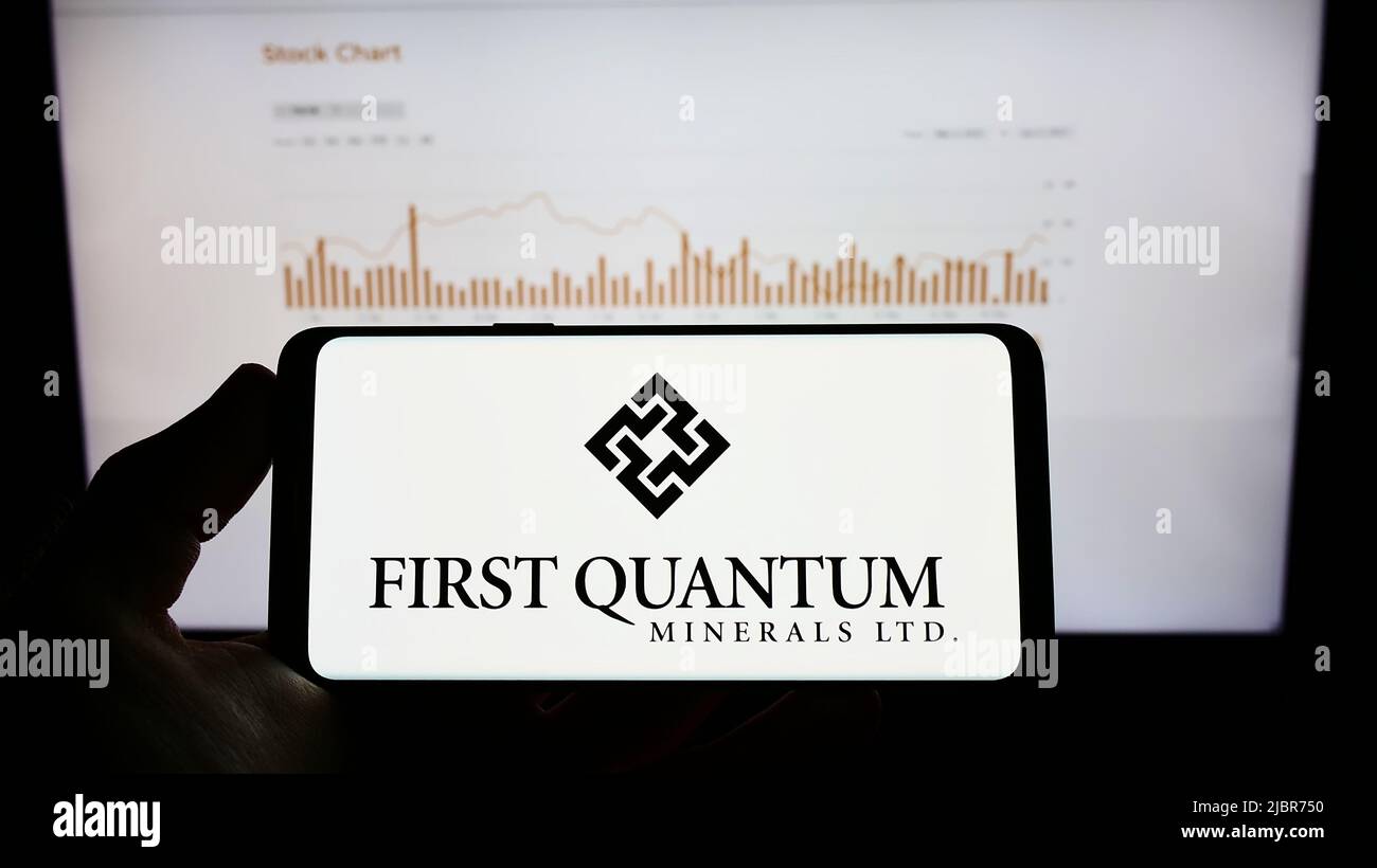 Person holding mobile phone with logo of mining company First Quantum ...