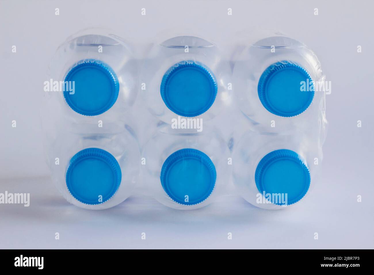 Six small pet bottles of natural spring water lay on the gray ...