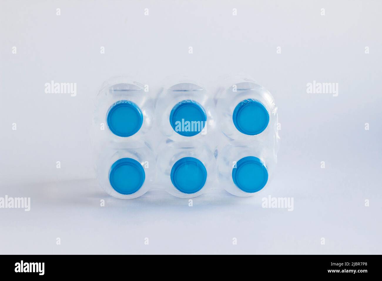 Six small pet bottles of natural spring water lay on the gray ...