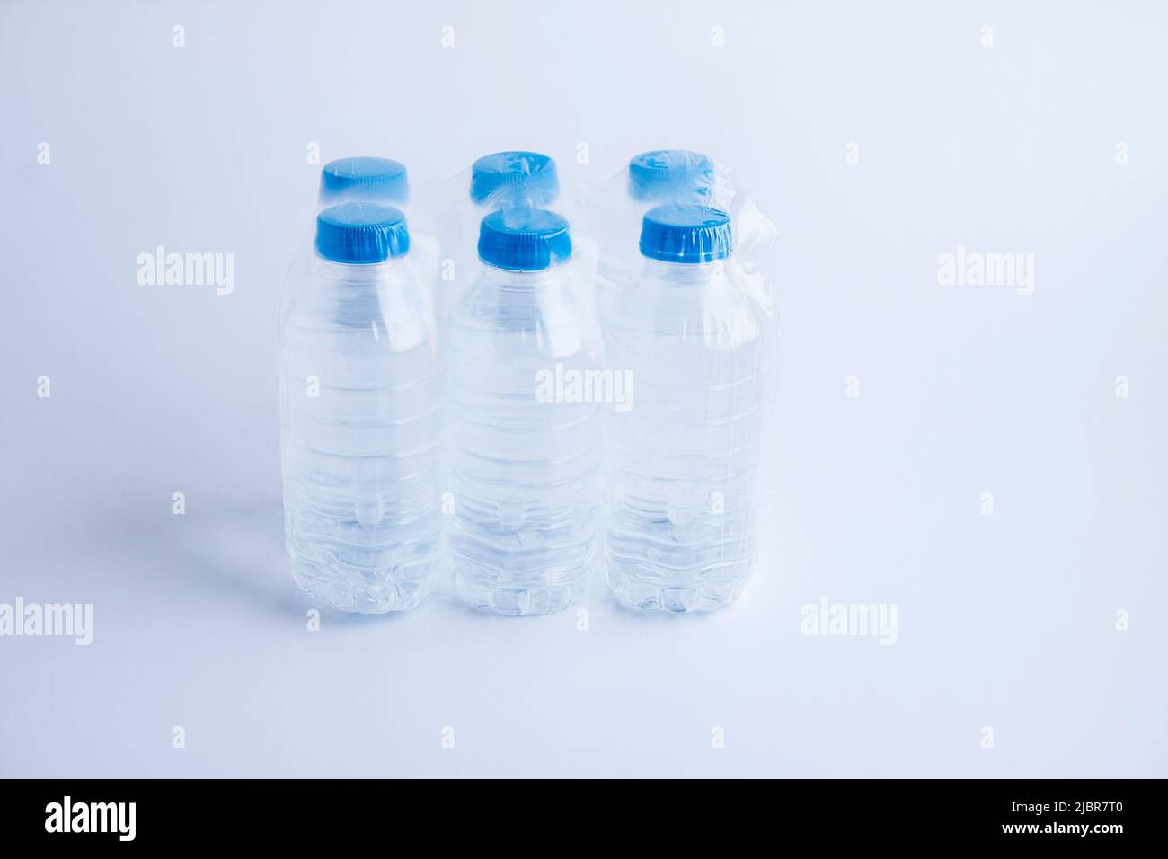 Six small pet bottles of natural spring water in transparent packing ...