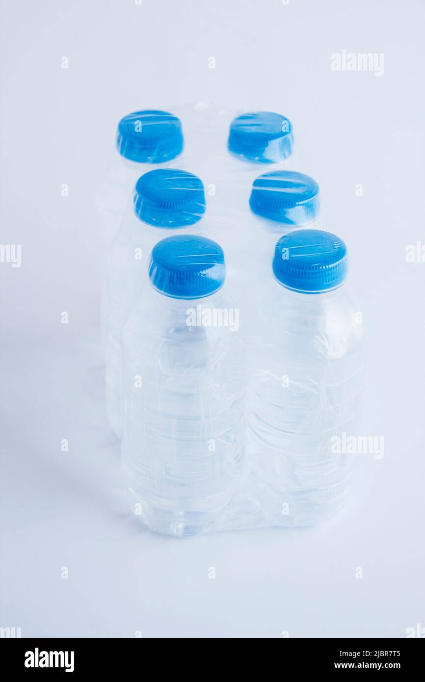Six small pet bottles of natural spring water in transparent packing ...