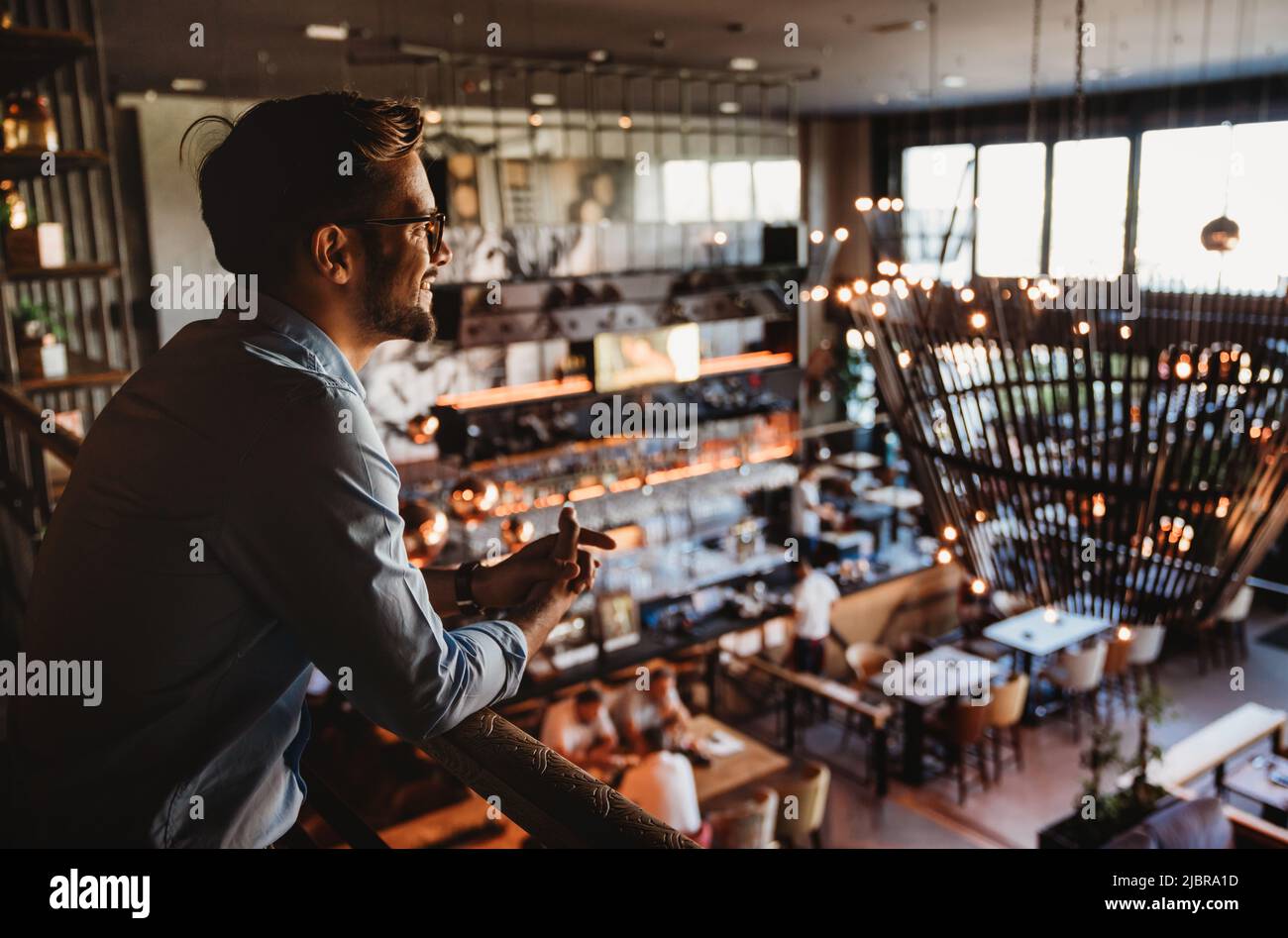 Happy businessman, restaurant owner proudly looking at crowded ...