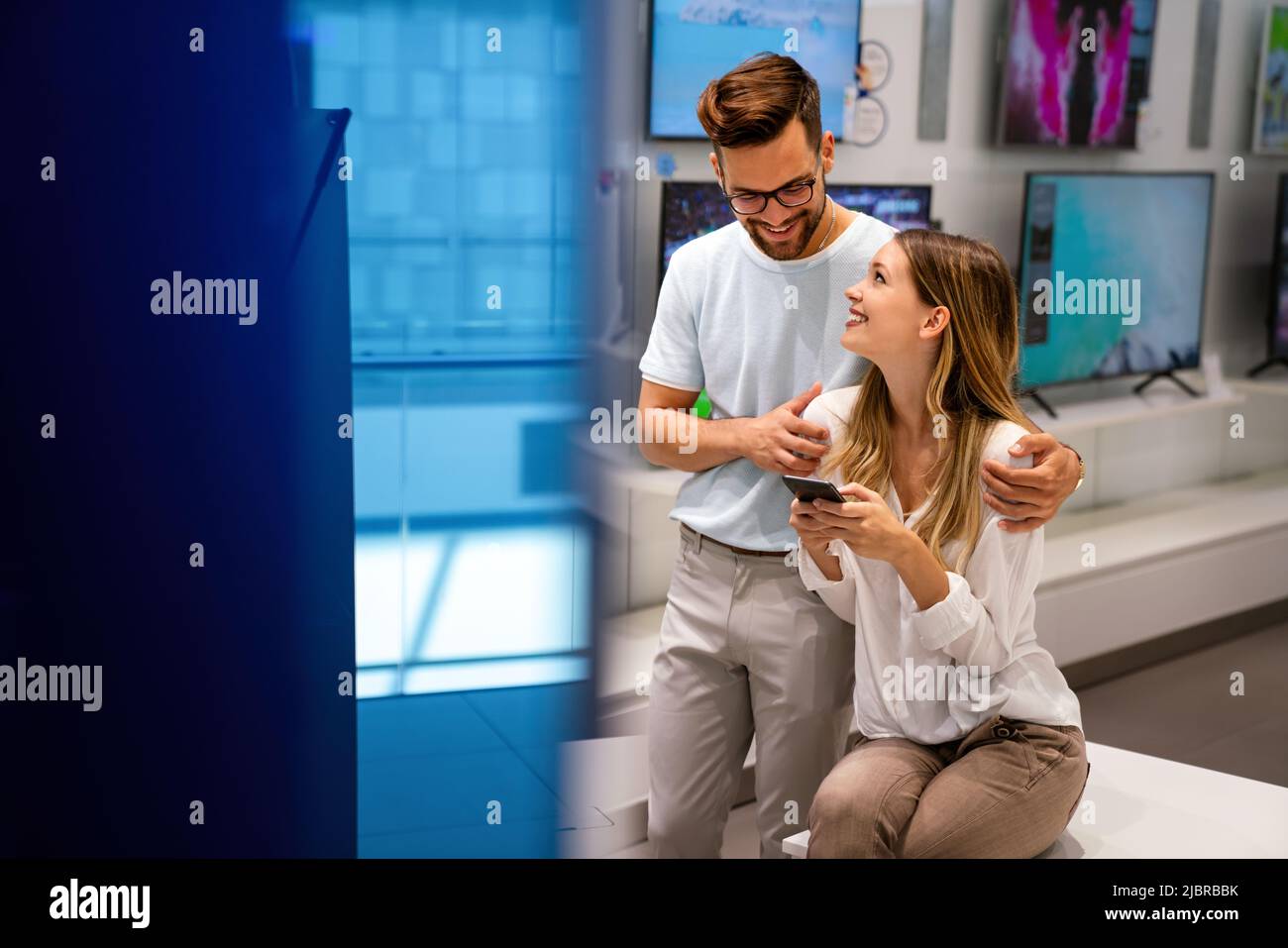 Happy people in consumer electronics retail store looking at new ...