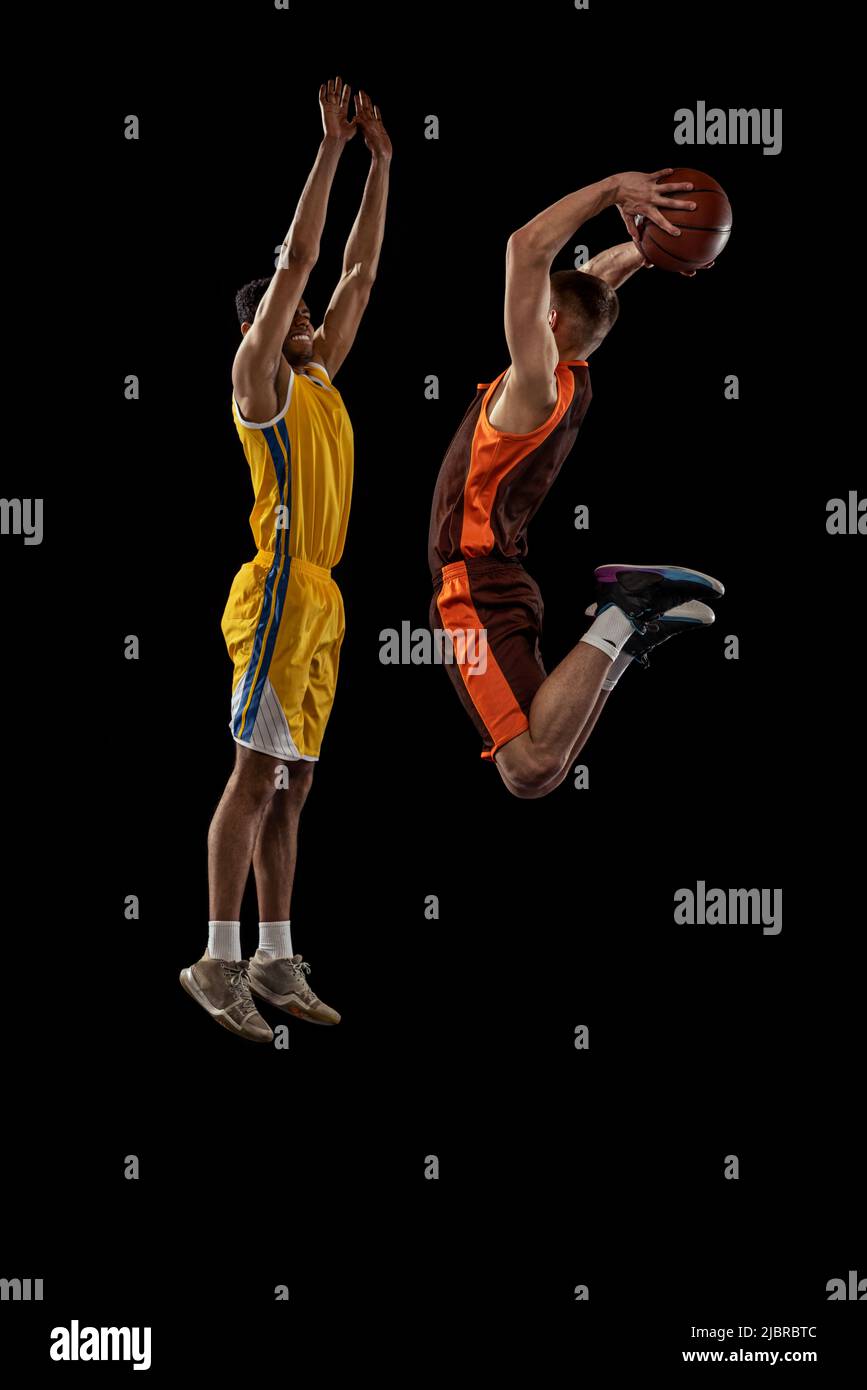 Portrait of two young men, professional basketball players in motion ...