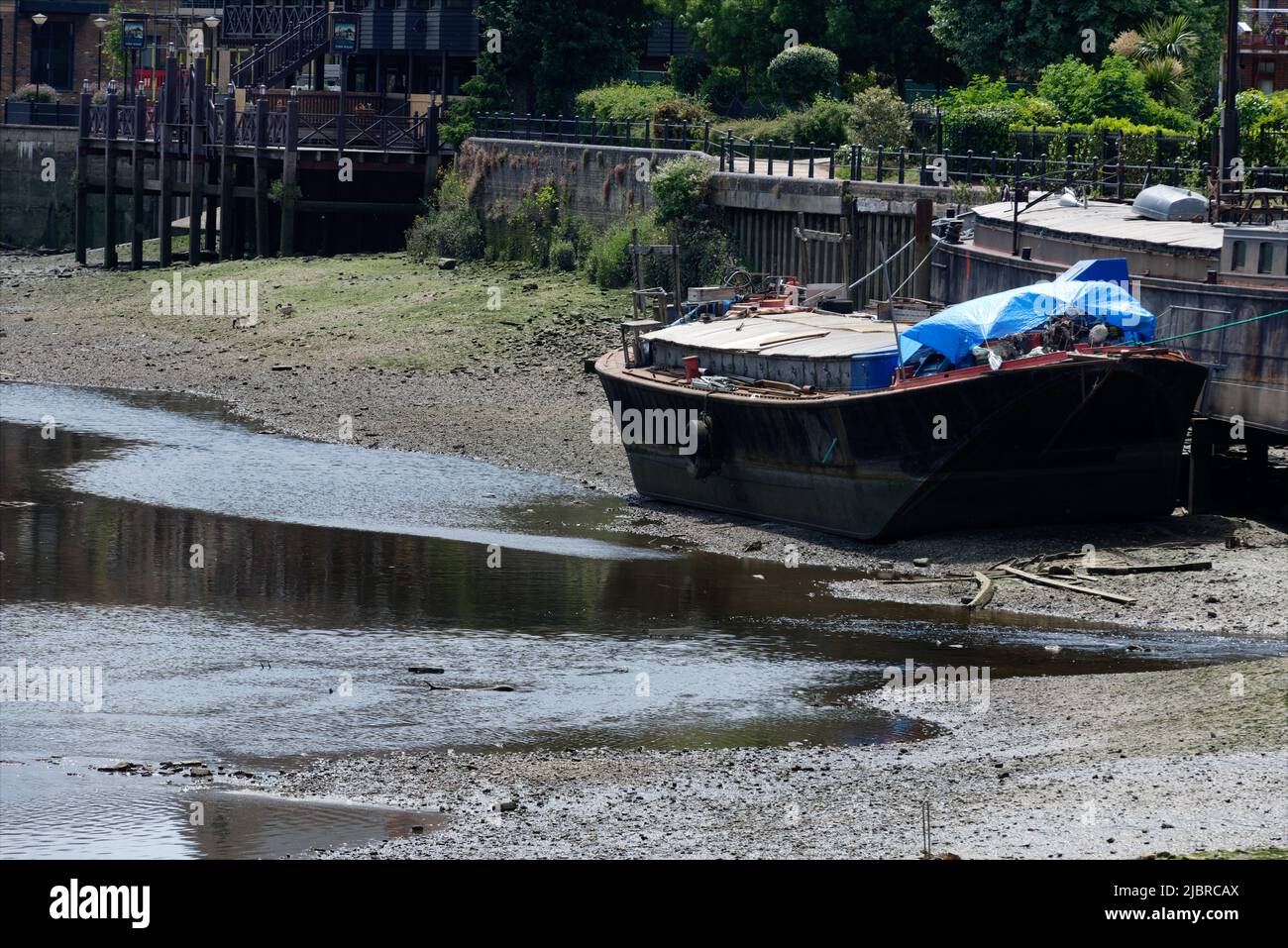 Boat sitting on the riverbed of the River Thames, low tide at Isleworth ...