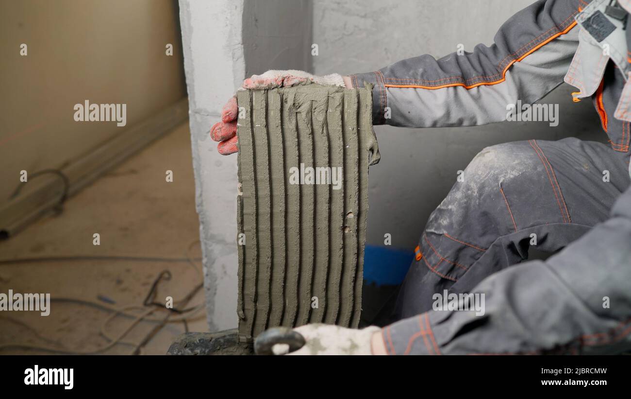Applying mortar to tiles, close-up. The master of laying tiles, takes a ...