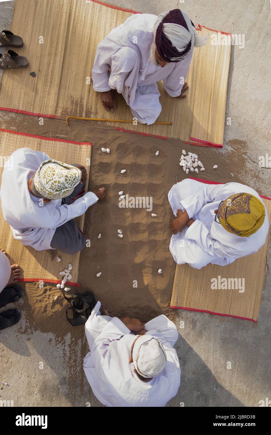Omani men playing the traditional Hawalis board game on the ground ...