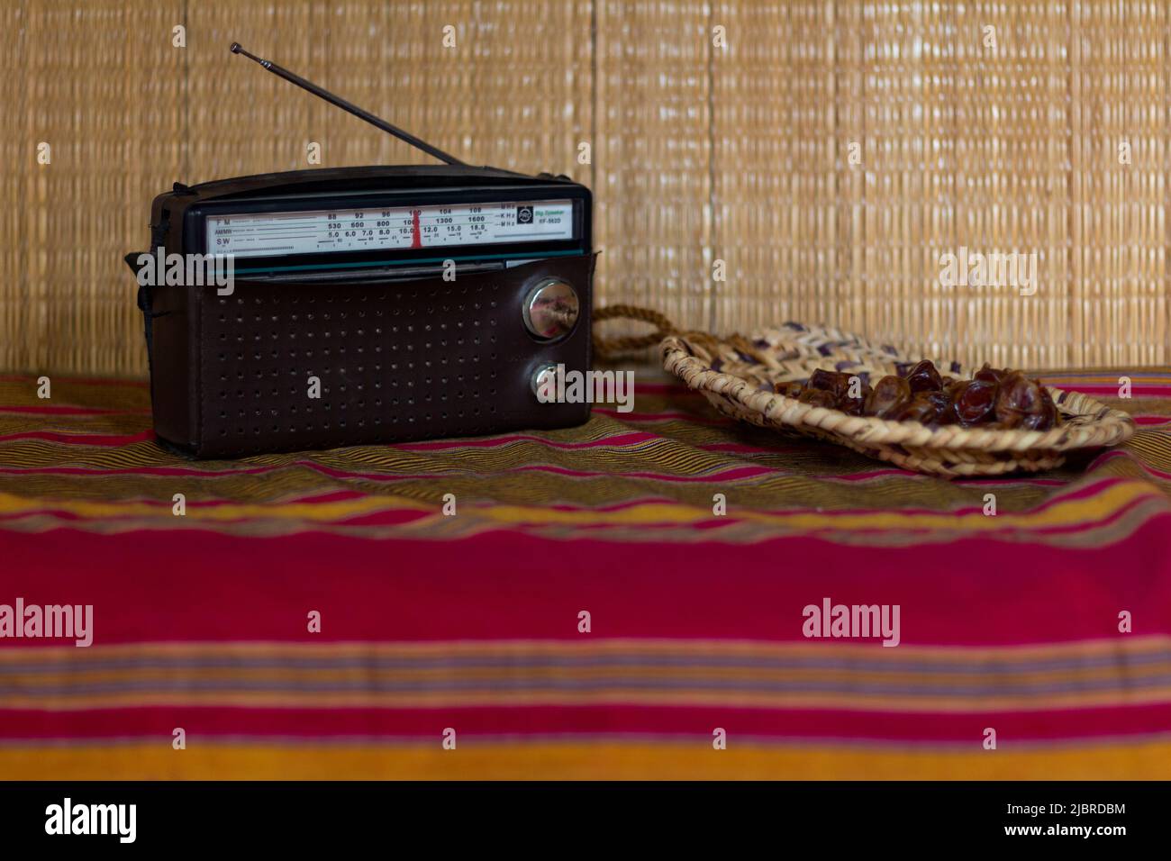 Vintage radio and traditional Omani dates displayed on a woven mat ...