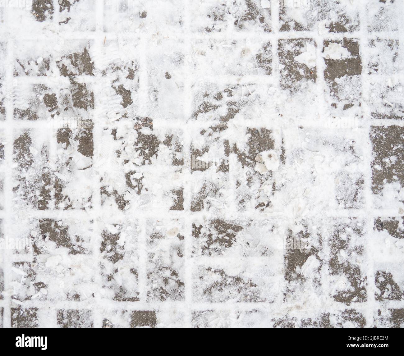 Snowy street tiles texture. Stone masonry on the pavement. Footprint in ...