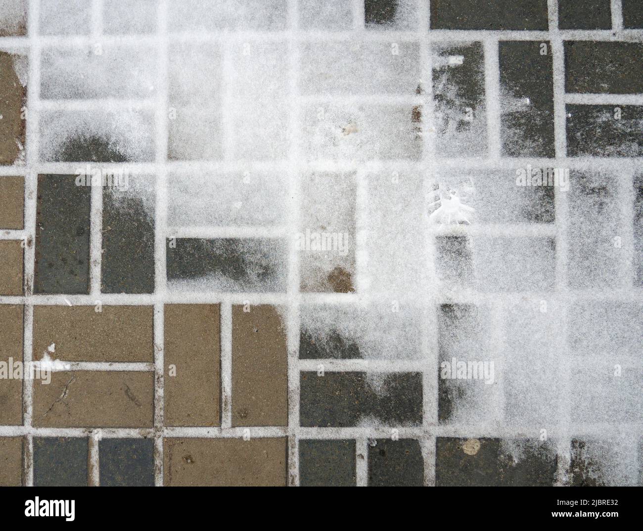 Snowy street tiles texture. Stone masonry on the pavement. Footprint in ...