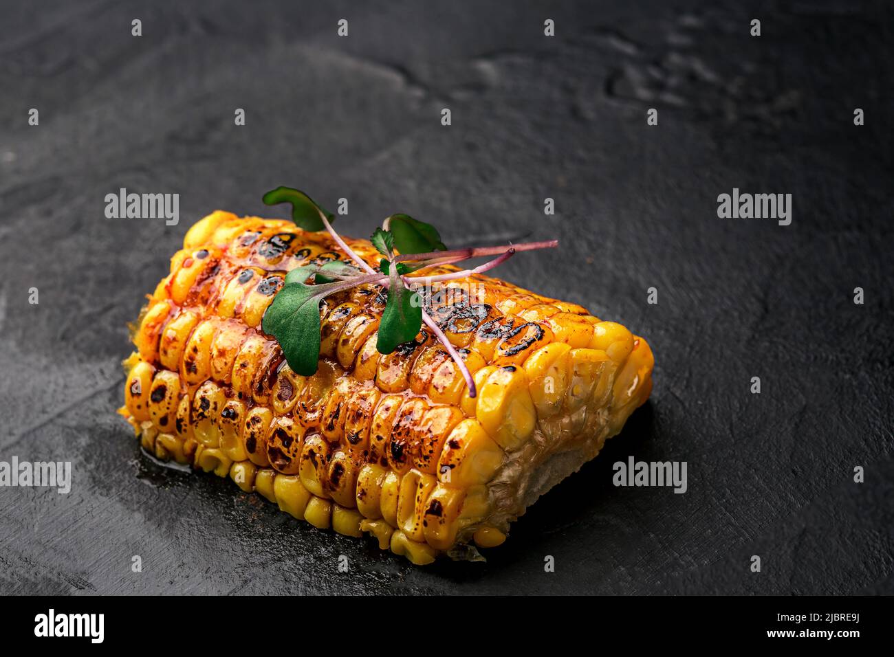Fresh grilled corn cob on a dark stone background, copy space, top view ...