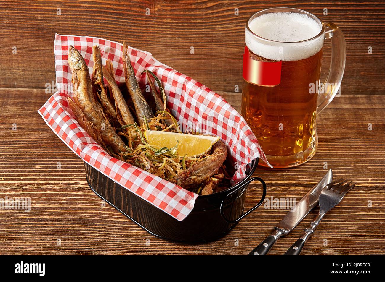 Snack to beer - fried small fish, lemon with a glass of light beer on a ...