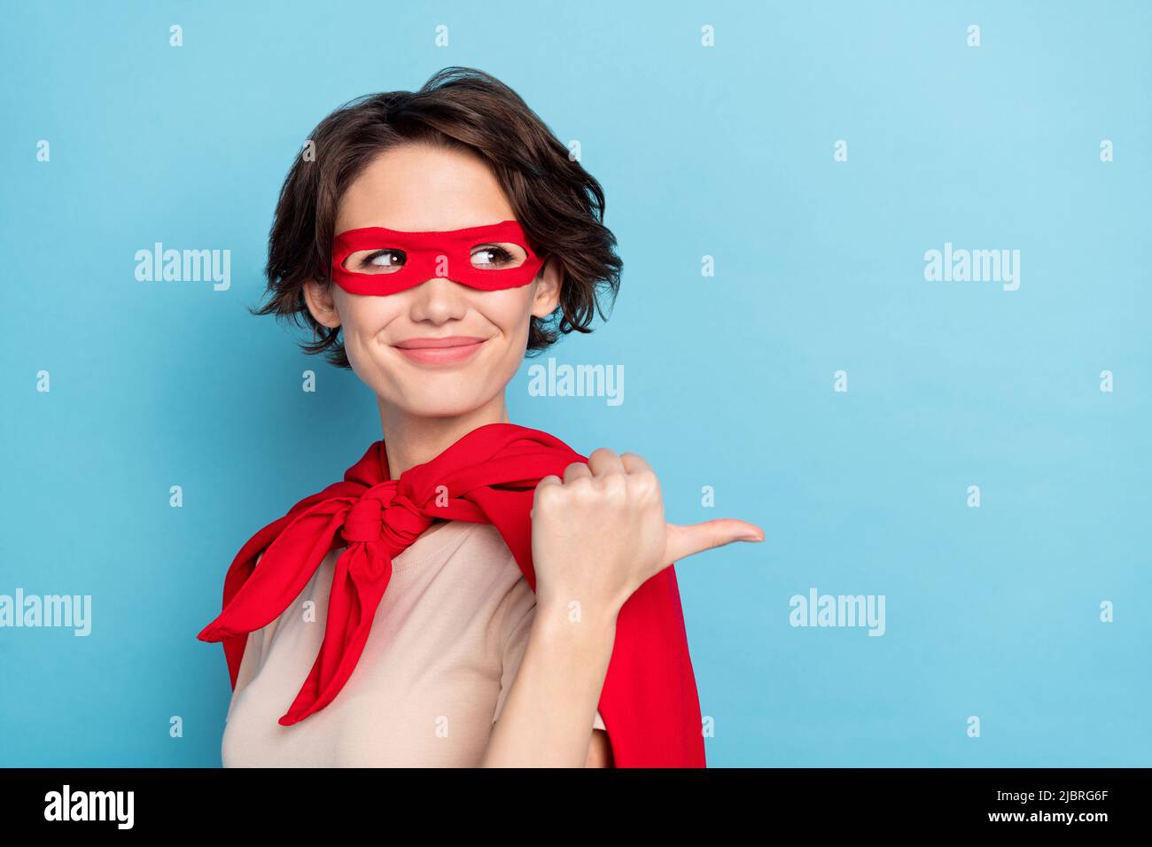Photo of sweet charming woman wear red cape pointing thumb back looking ...