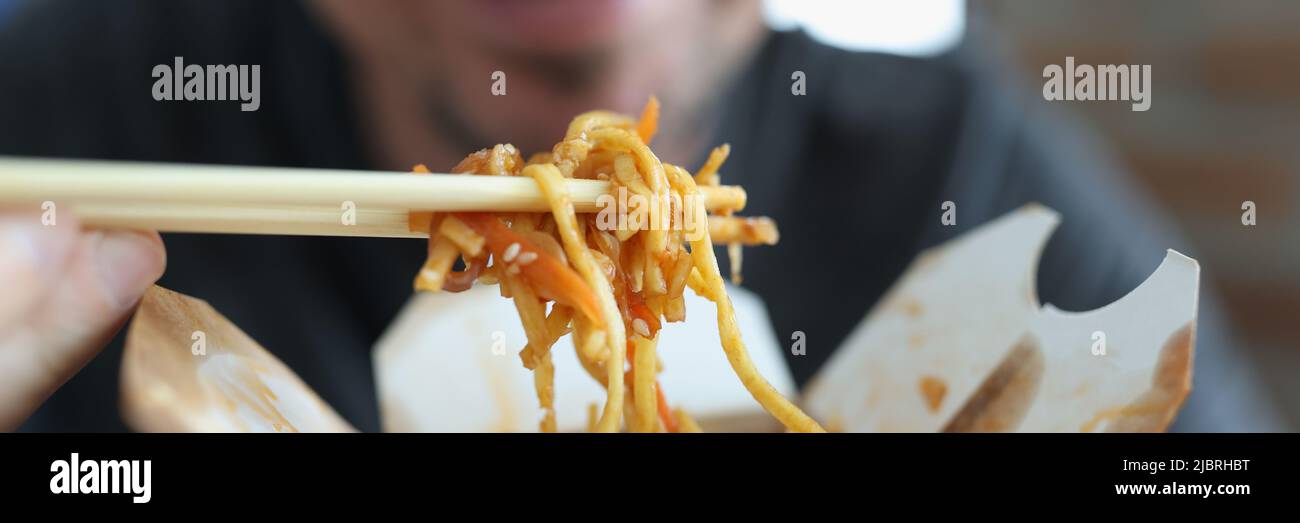 Smiling man eating spicy noodle chinese food with vegetable using ...