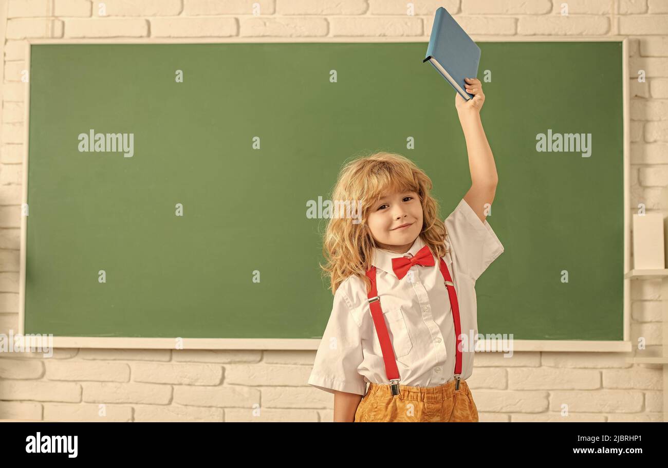 positive child boy in bow tie study in school classrrom with notebook ...