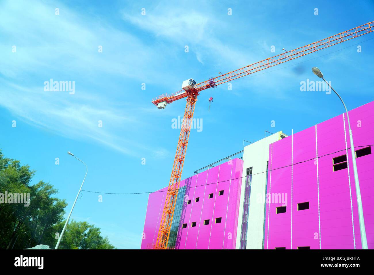 Construction crane near a pink building under construction against a ...