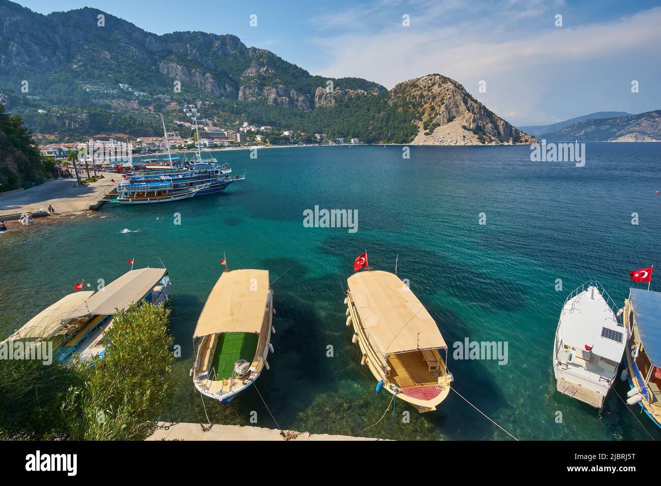 small boats moored in Aegean sea blue lagoon with mountainous islands ...