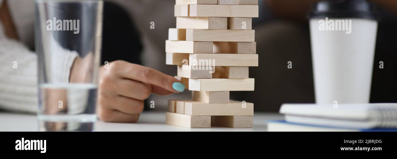 Womans hand pull one of wooden blocks from high build tower Stock Photo ...