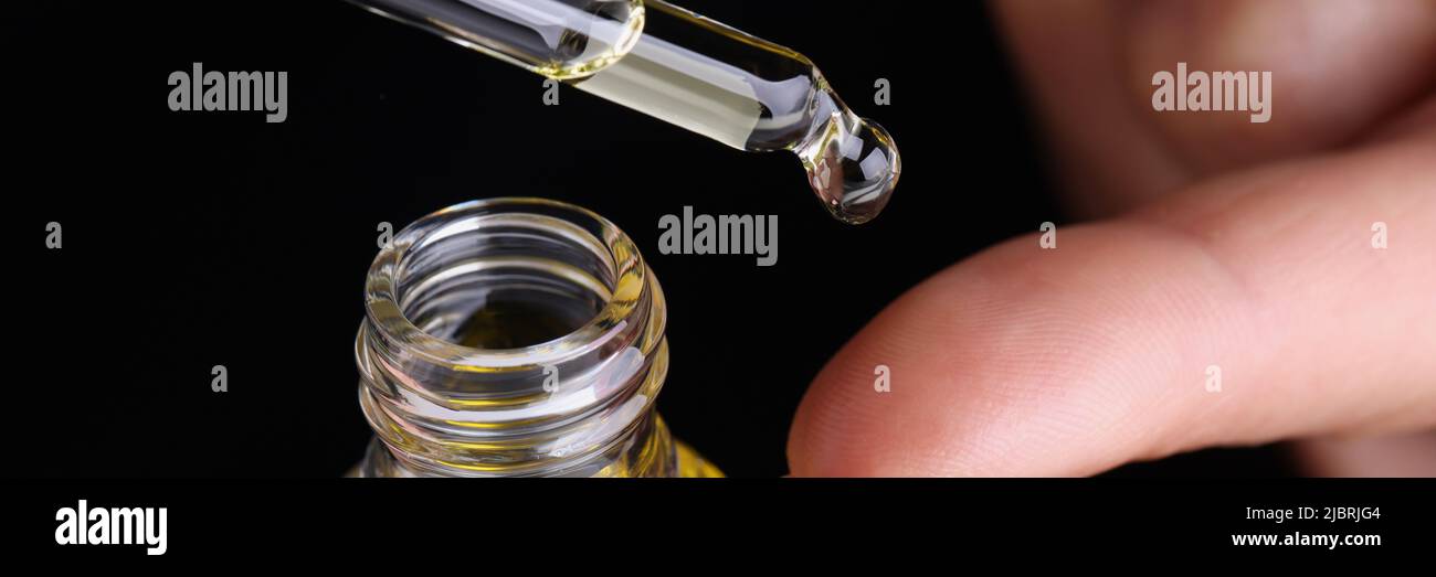 Person dripping drop of extract oil on finger with eyedropper Stock ...