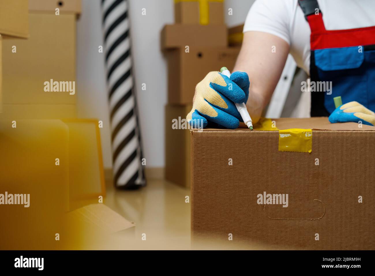 Man mover in uniform packing boxes for relocation Stock Photo - Alamy