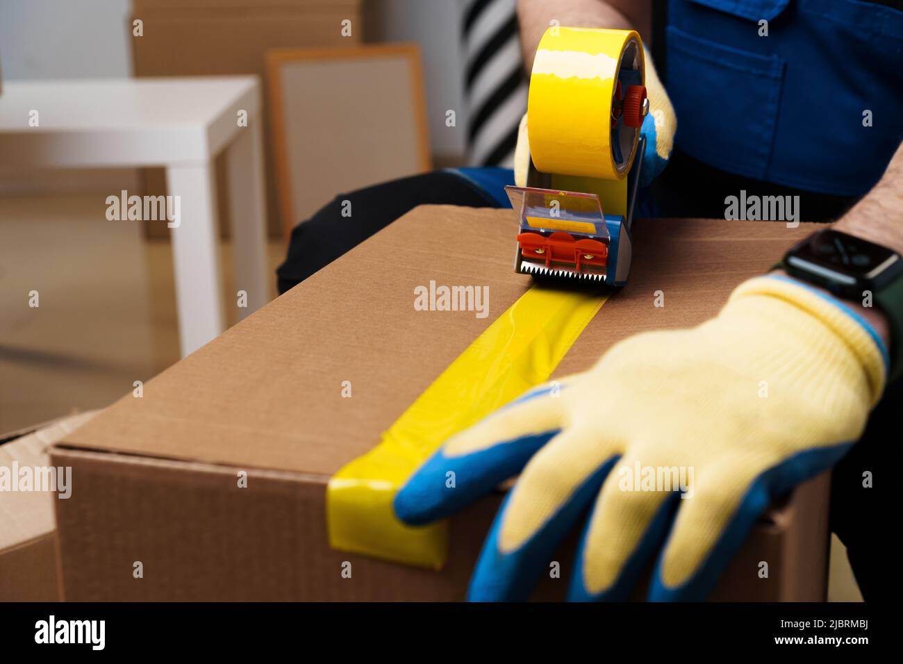Man mover in uniform packing boxes with scotch tape Stock Photo - Alamy