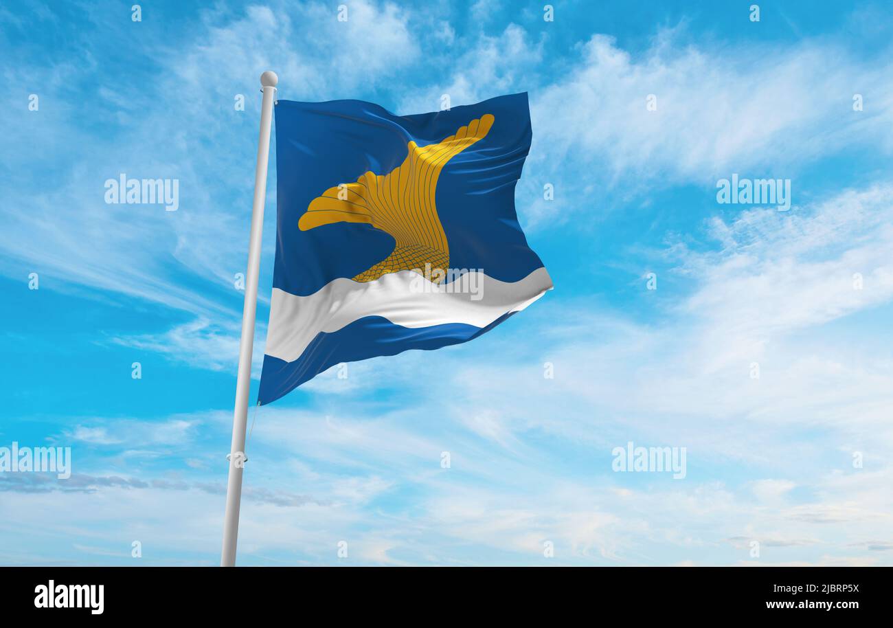 official flag of Vantaa , Finland at cloudy sky background on sunset ...