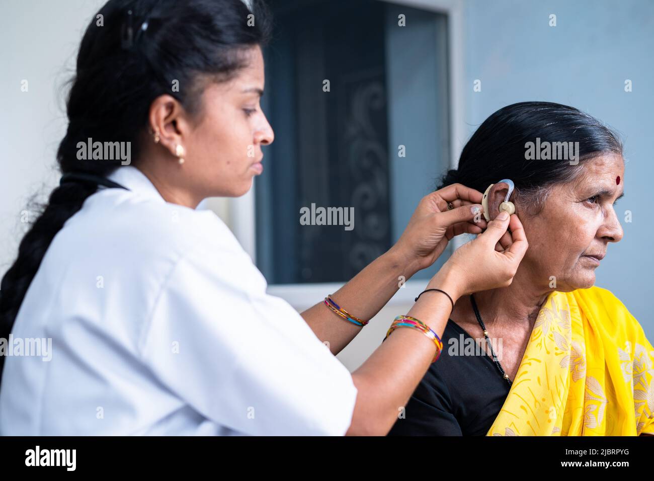 Happy senior woman getting fixed with hearing aid machine from doctor ...