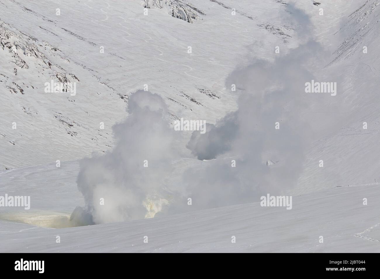 Steam rises from fumaroles on active volcano in snowy winter landscape ...
