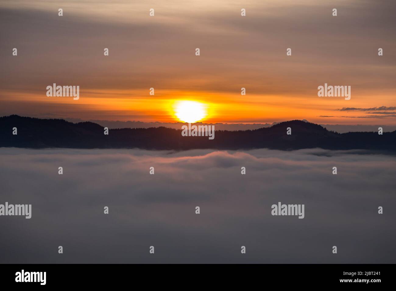 Morning orange sunbeams over misty clouds in the hazy mountains, orange ...