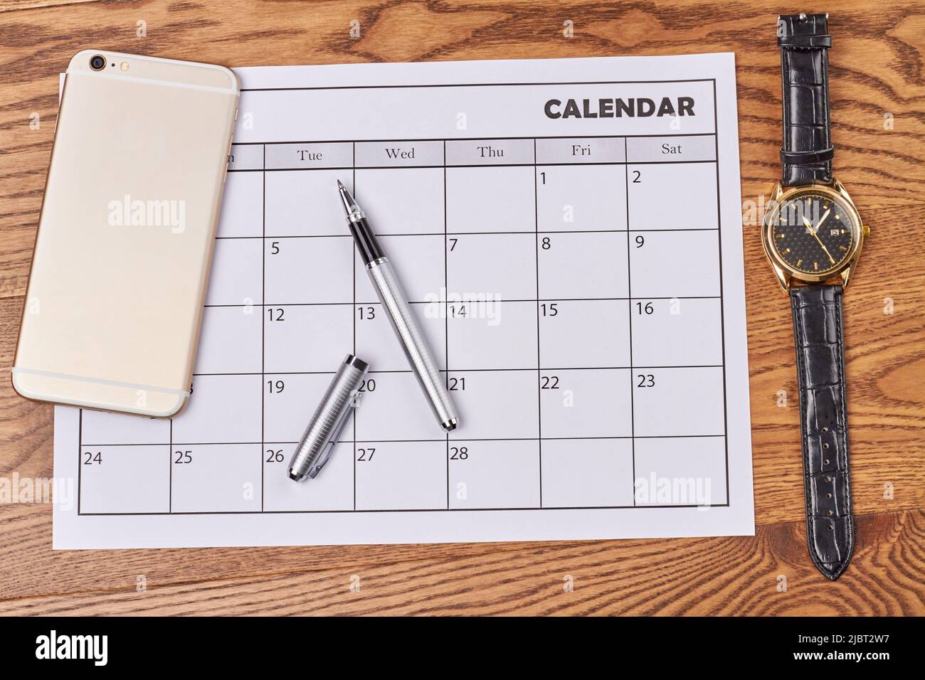 Calendar with smartphone pen and watch clock on brown wooden desk ...