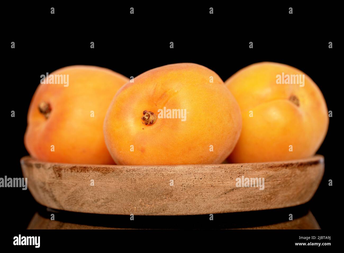 Three ripe sweet apricots with a wooden tray, close-up, isolated on a ...