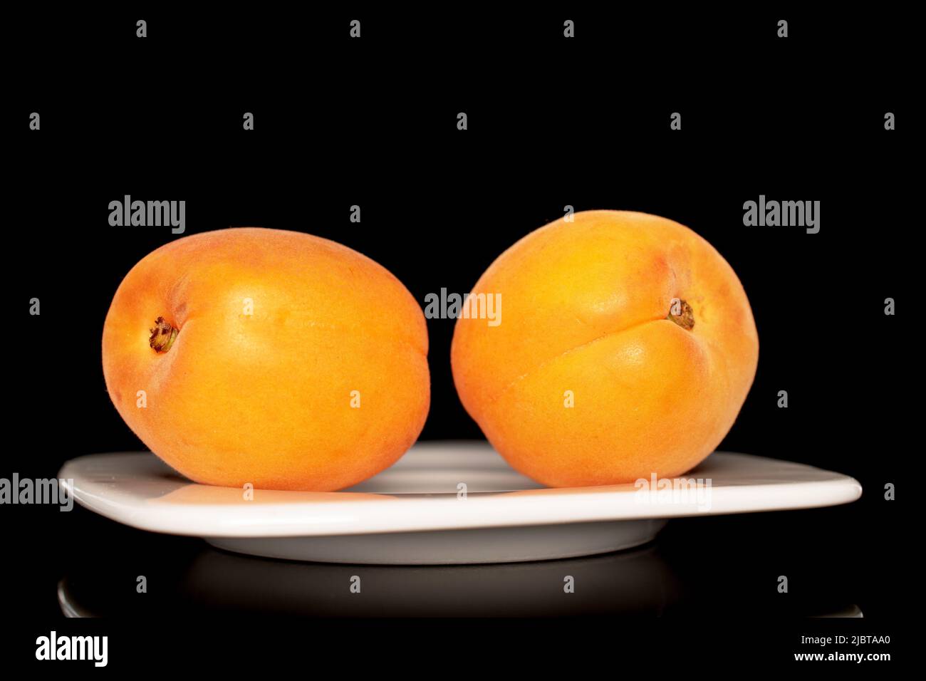 Two ripe sweet apricots with white ceramic dishes, close-up, isolated ...