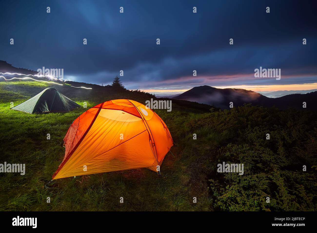 Illuminated orange camping tent under moon at night Stock Photo - Alamy