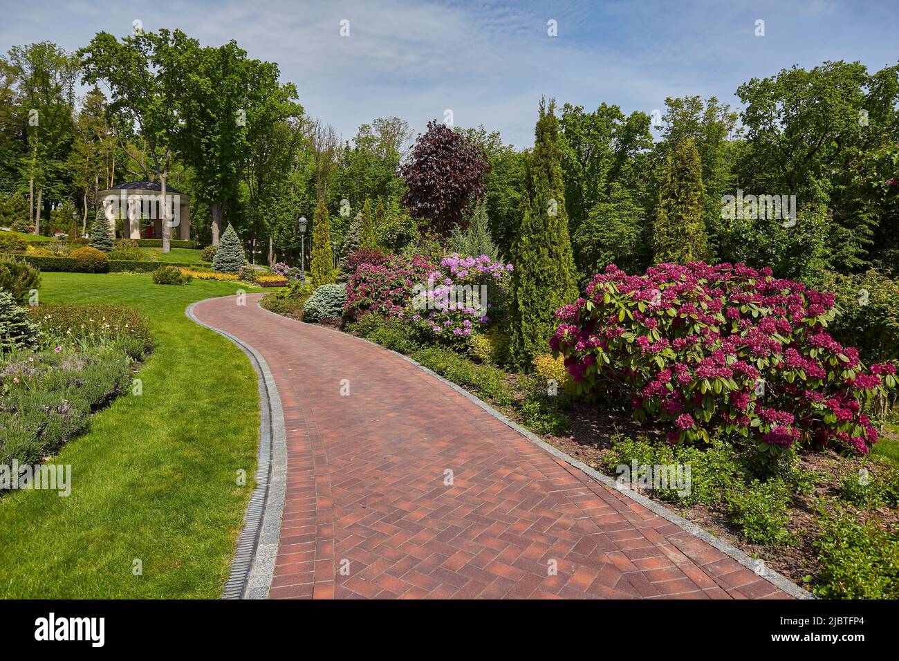 Jogging track in garden of public park among greenery trees, flower ...