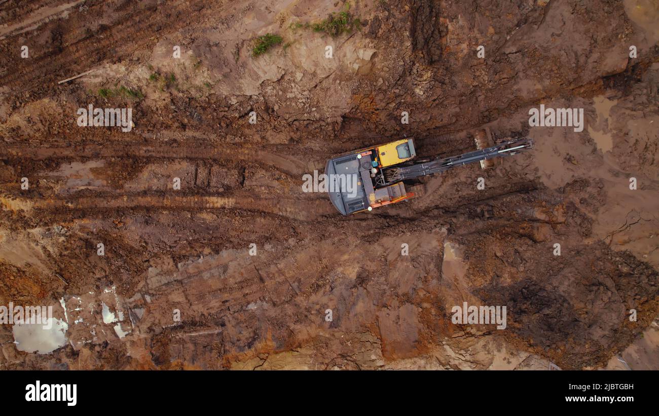 Aerial view of an excavator digging up the road on a construction site ...