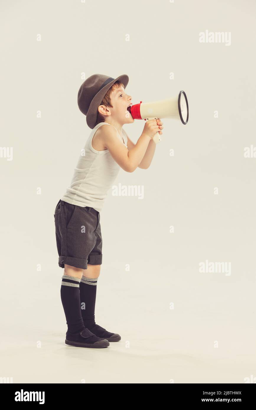 Portrait of little boy, child shouting in megaphone, playing isolated ...