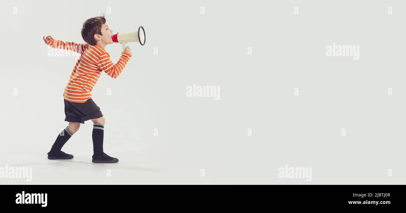 Portrait of little boy, child shouting in megaphone, playing isolated ...