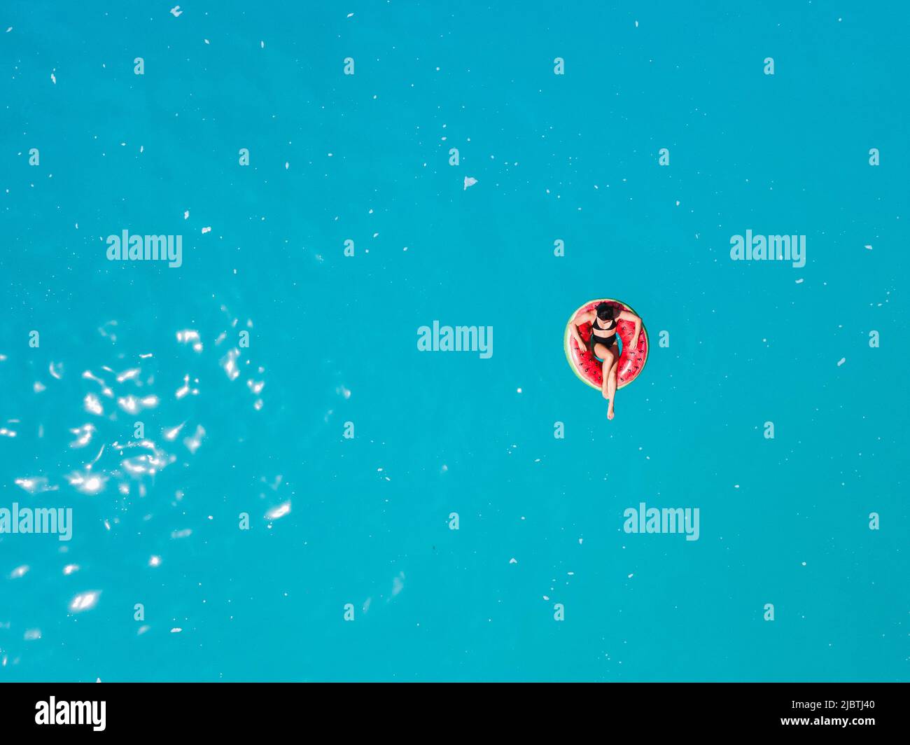 overhead view of woman floating on inflatable ring in blue sea water ...