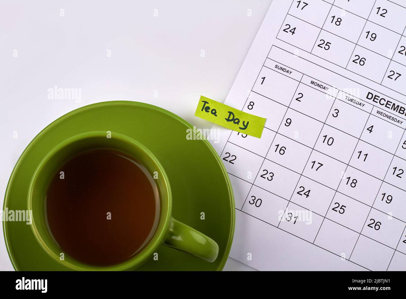 Top view cup of tea and month calendar on white desk. Tea day concept ...