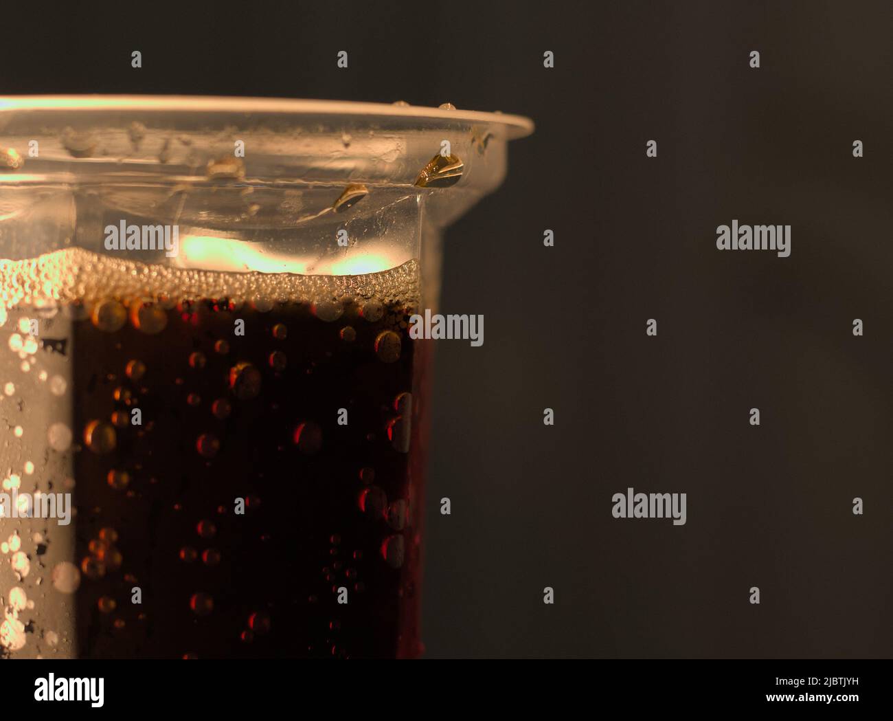 Cola with fizz in a plastic glass. Closeup, night Stock Photo - Alamy