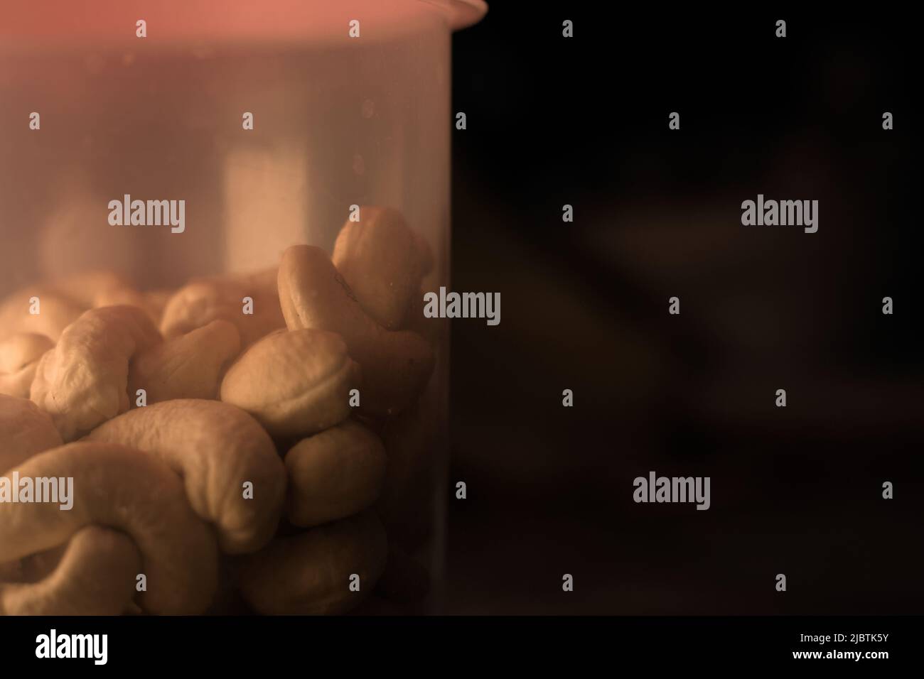 Tasty looking cashews in container. Dramatic setup. Closeup. Text space ...