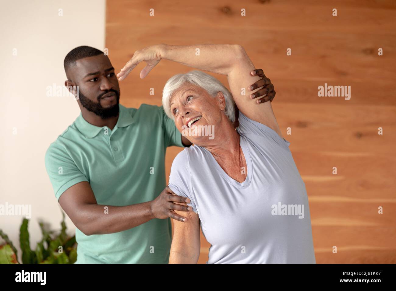 African american male physiotherapist helping caucasian senior woman to ...