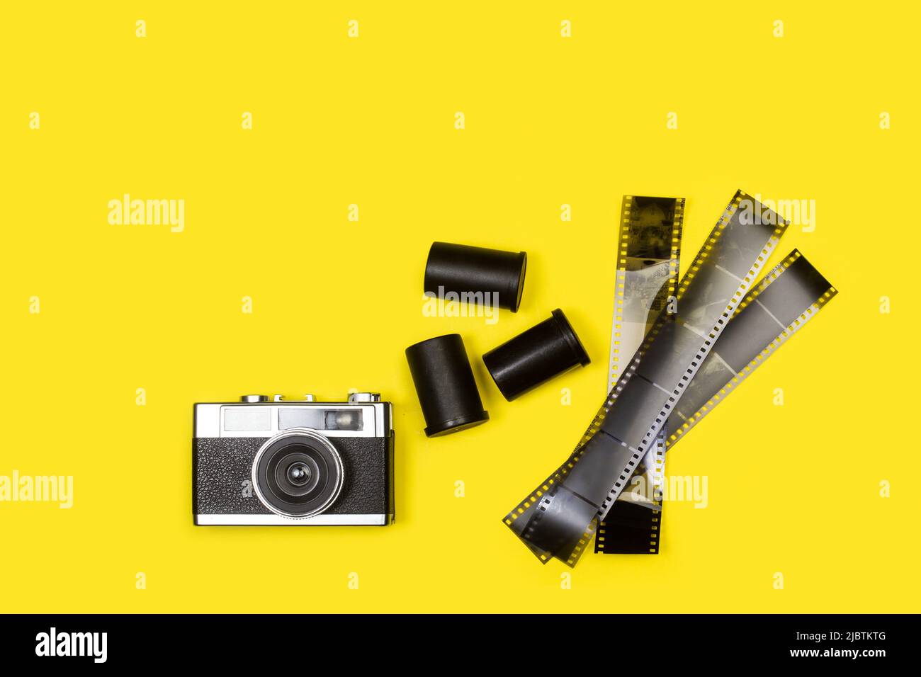 Vintage photographic camera and film negatives on a yellow background ...