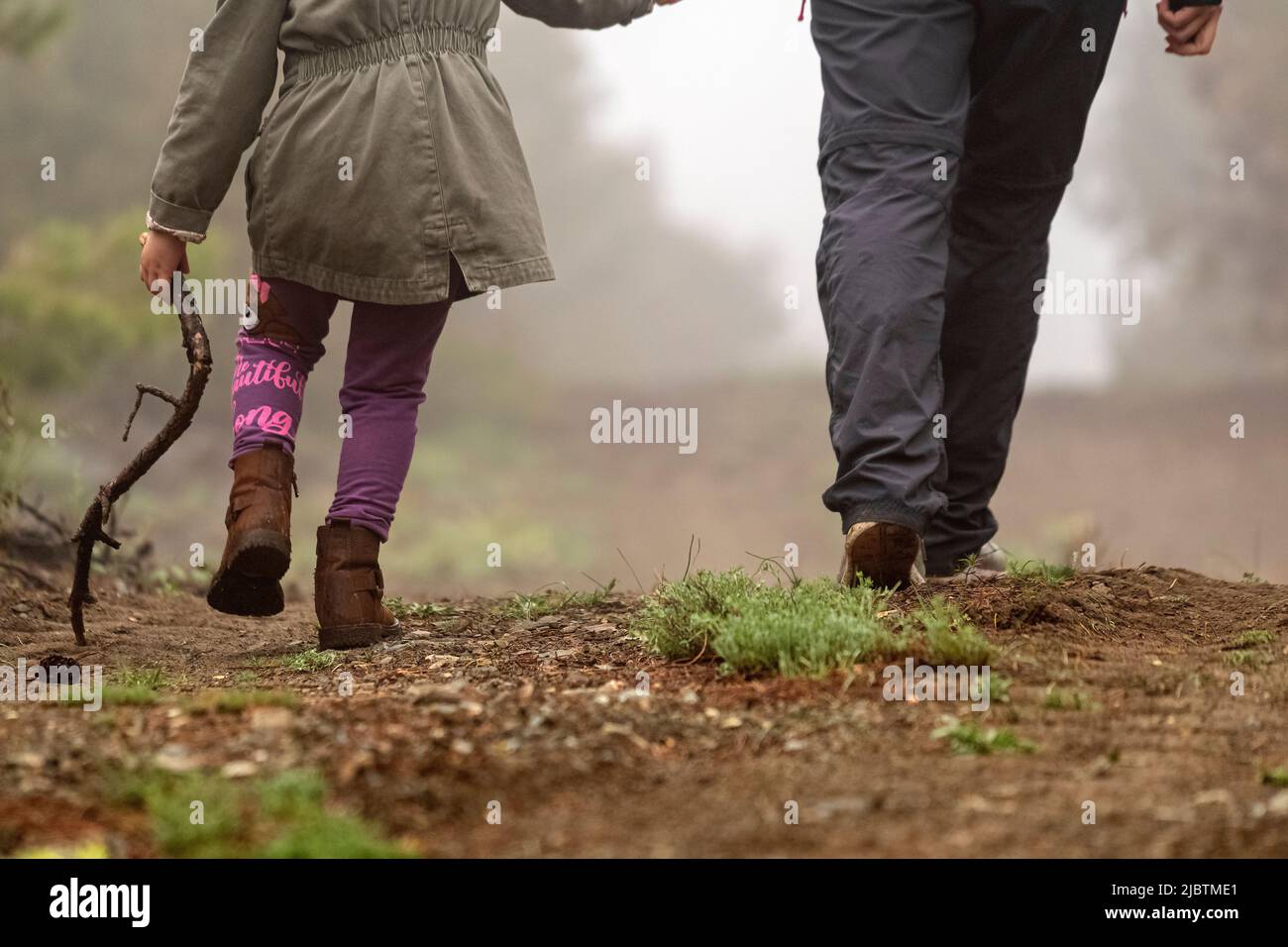 Selective focus shot of back feet of mother and daughter with stick ...