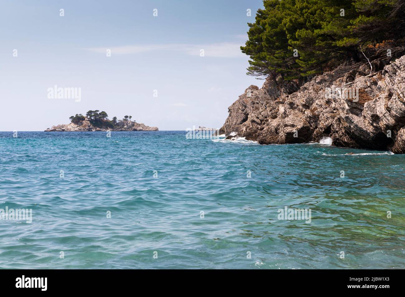 Blue sea with rocky cliffs and island in the distance Stock Photo - Alamy