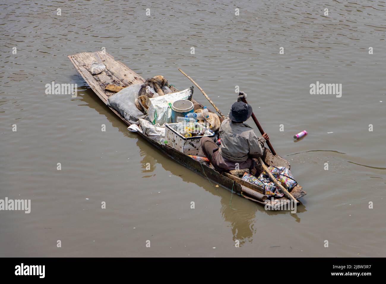 A poor human floats on an old boat full of recycled materials Stock ...