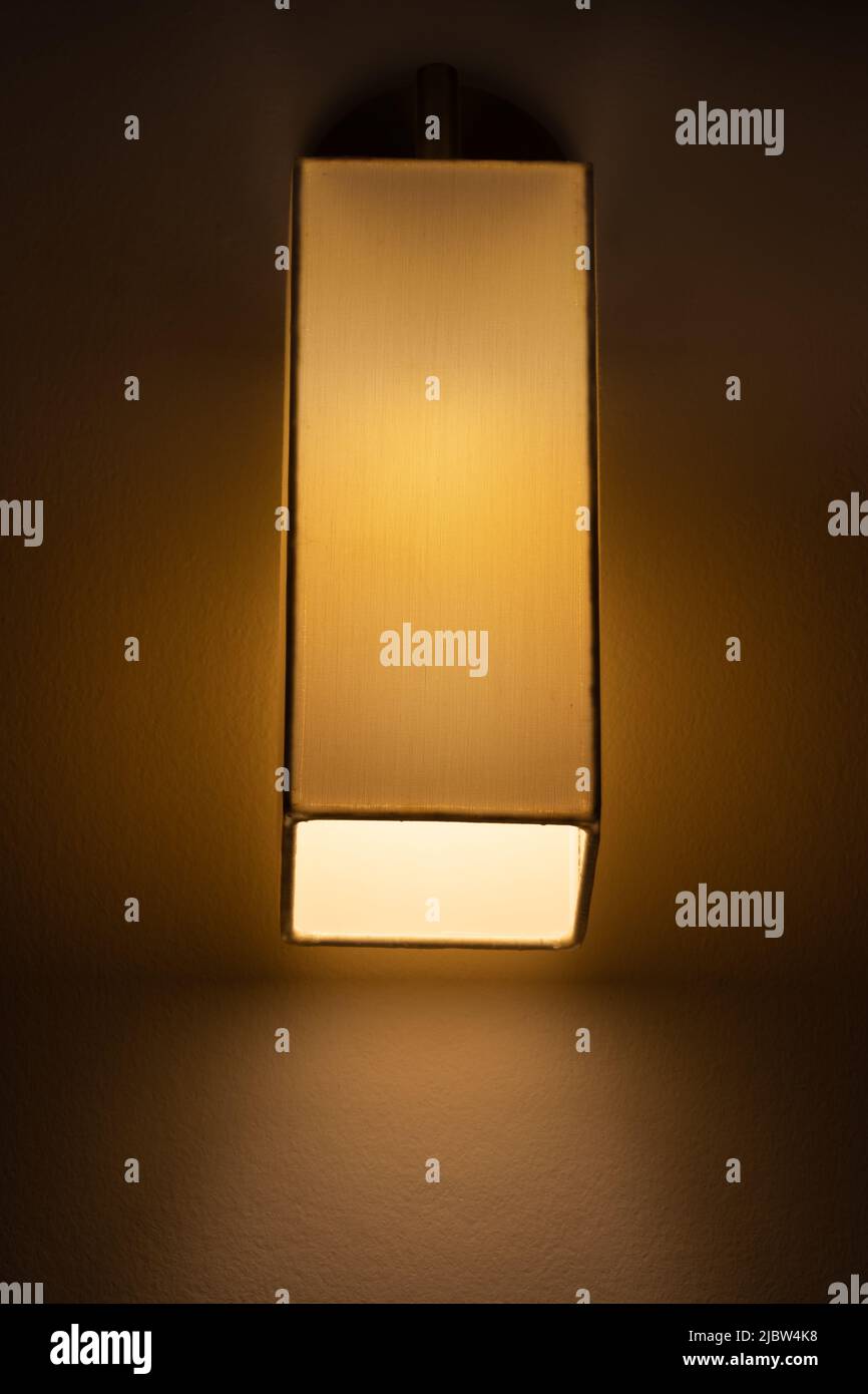 A textile lamp in the shape of a vertical block hangs on the wall Stock ...